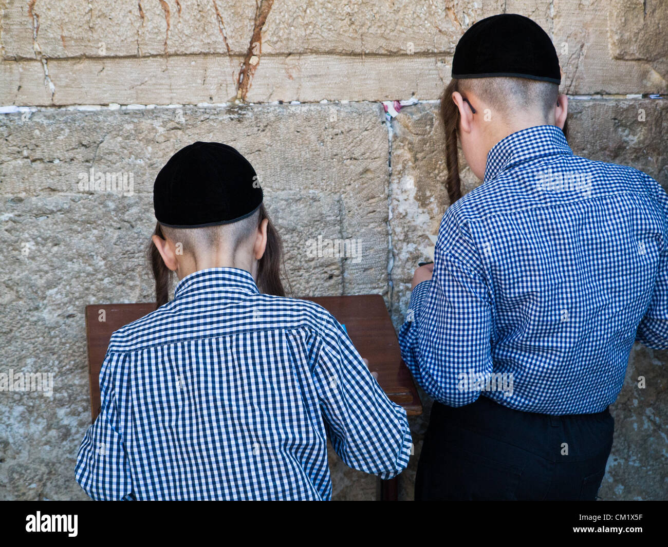 Two young boys with traditional long sidelocks pray at the Western Wall ...