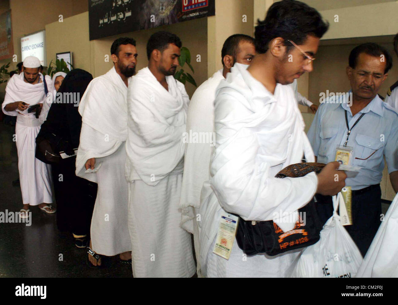 Pakistani pilgrims stand in a queue at Jinnah International Airport ...