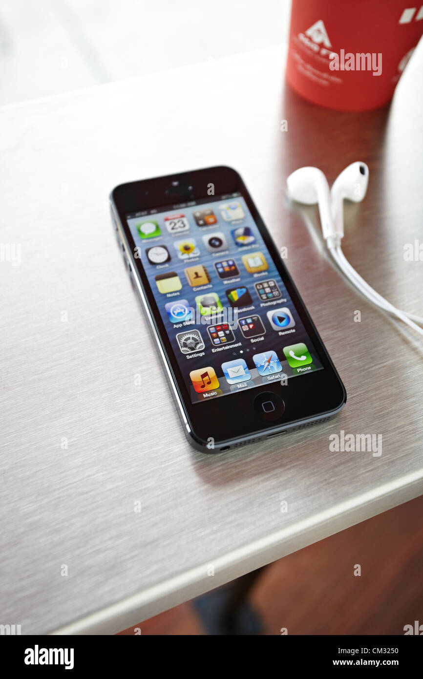Inside a coffee shop, a newly released, black, Apple iPhone 5 sits face ...