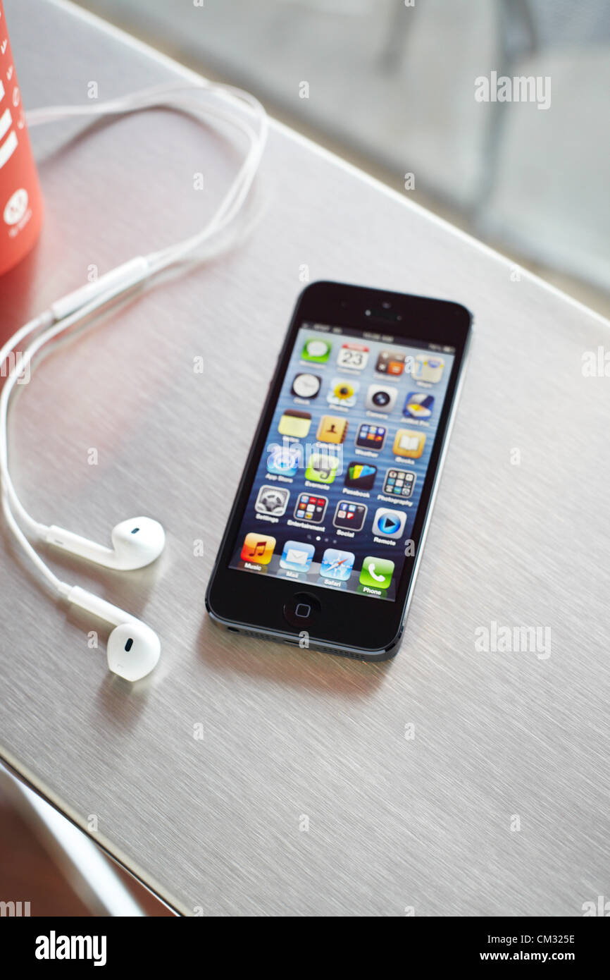 Inside a coffee shop, a newly released, black, Apple iPhone 5 sits face ...