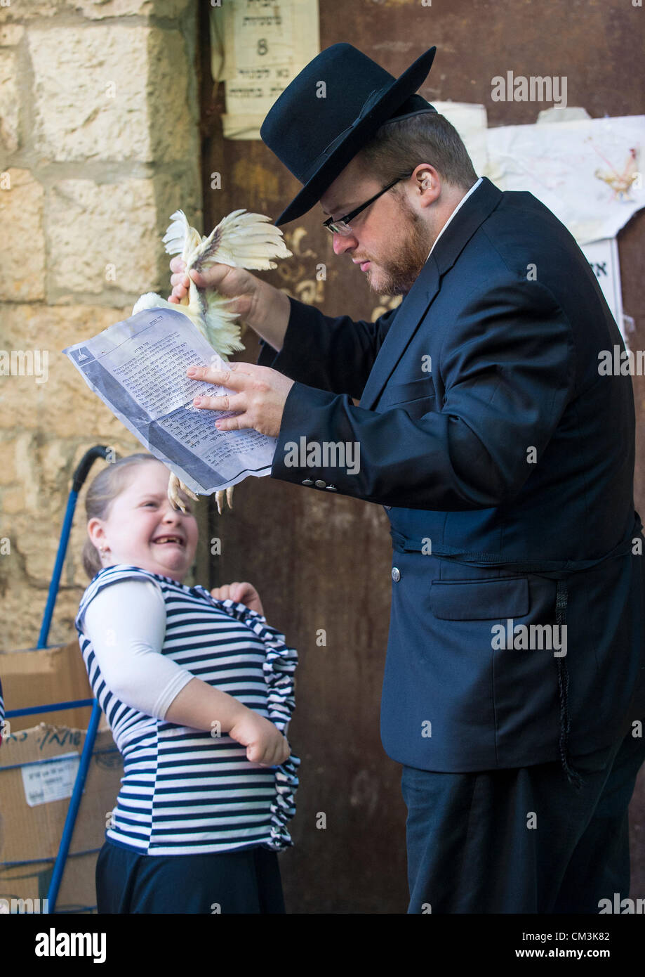 An ultra Orthodox Jewish man waves a chicken over his child's heads ...