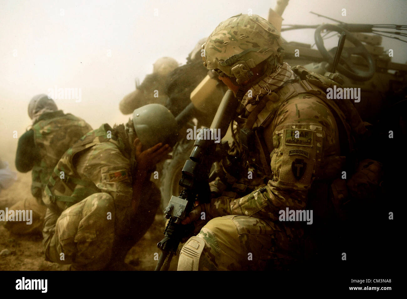 US Army soldiers take cover from flying debris kicked up by a CH-47 ...