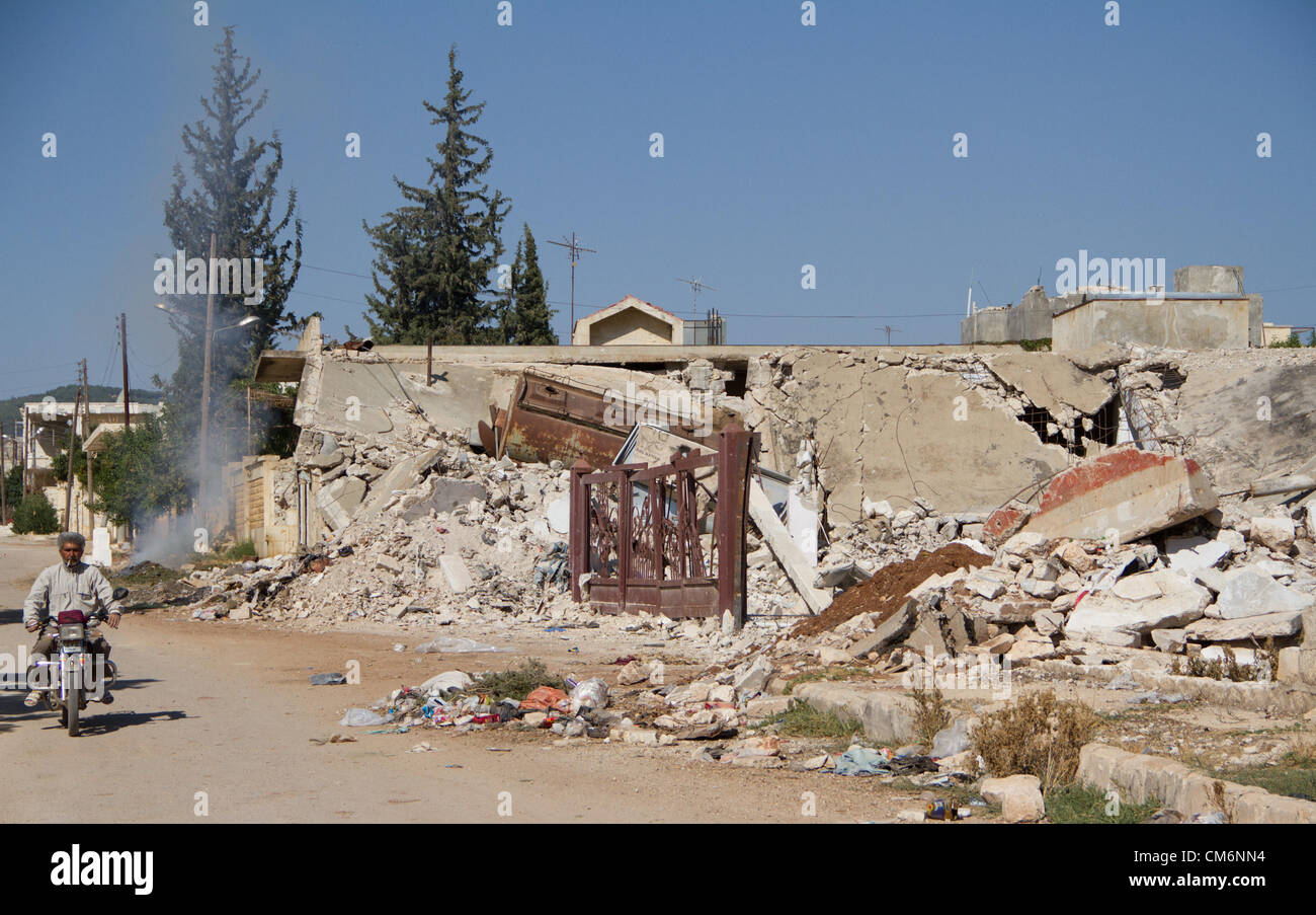 Azaz, Syria. 17th October 2012. A man rides by a building destroyed by ...