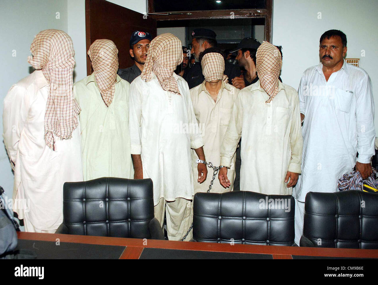 Police officials escort handcuffed accused (face covered with cloths ...