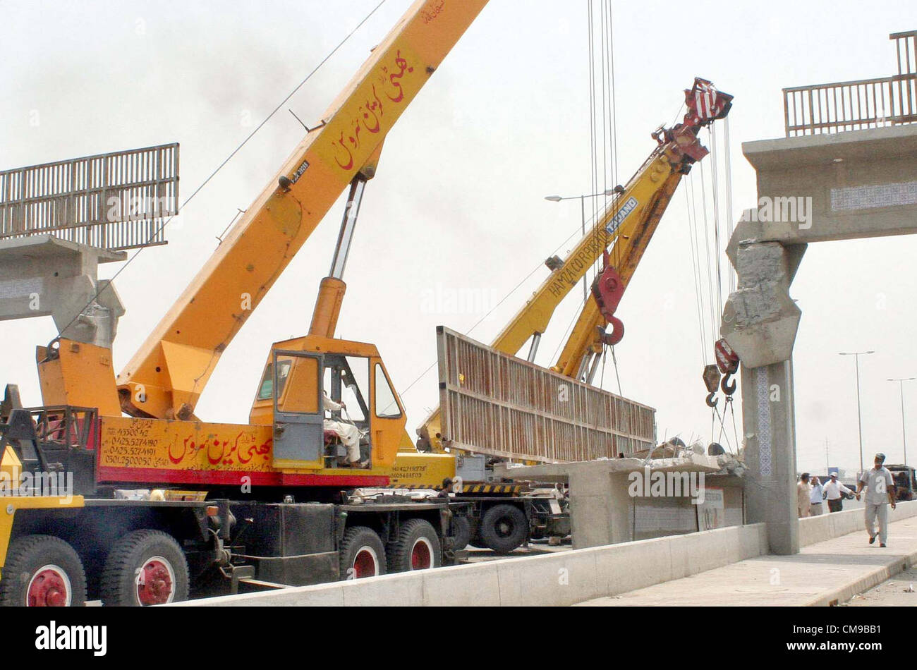 Heavy machinery lifting the wreckage of collapsed pedestrian bridge at ...
