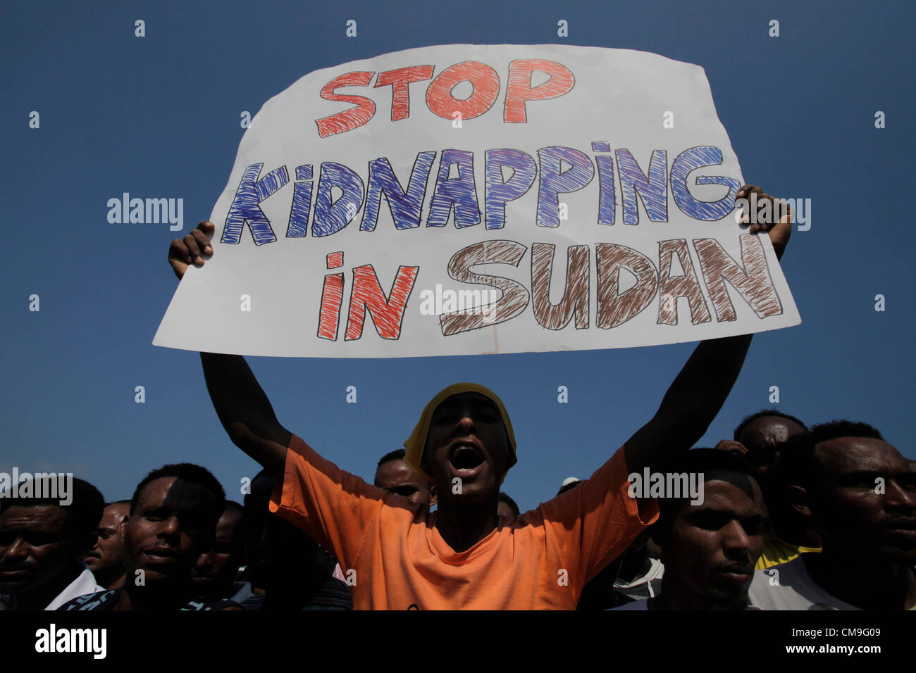 A demonstrator holds a paperboard sign which reads "Stop kidnapping in ...