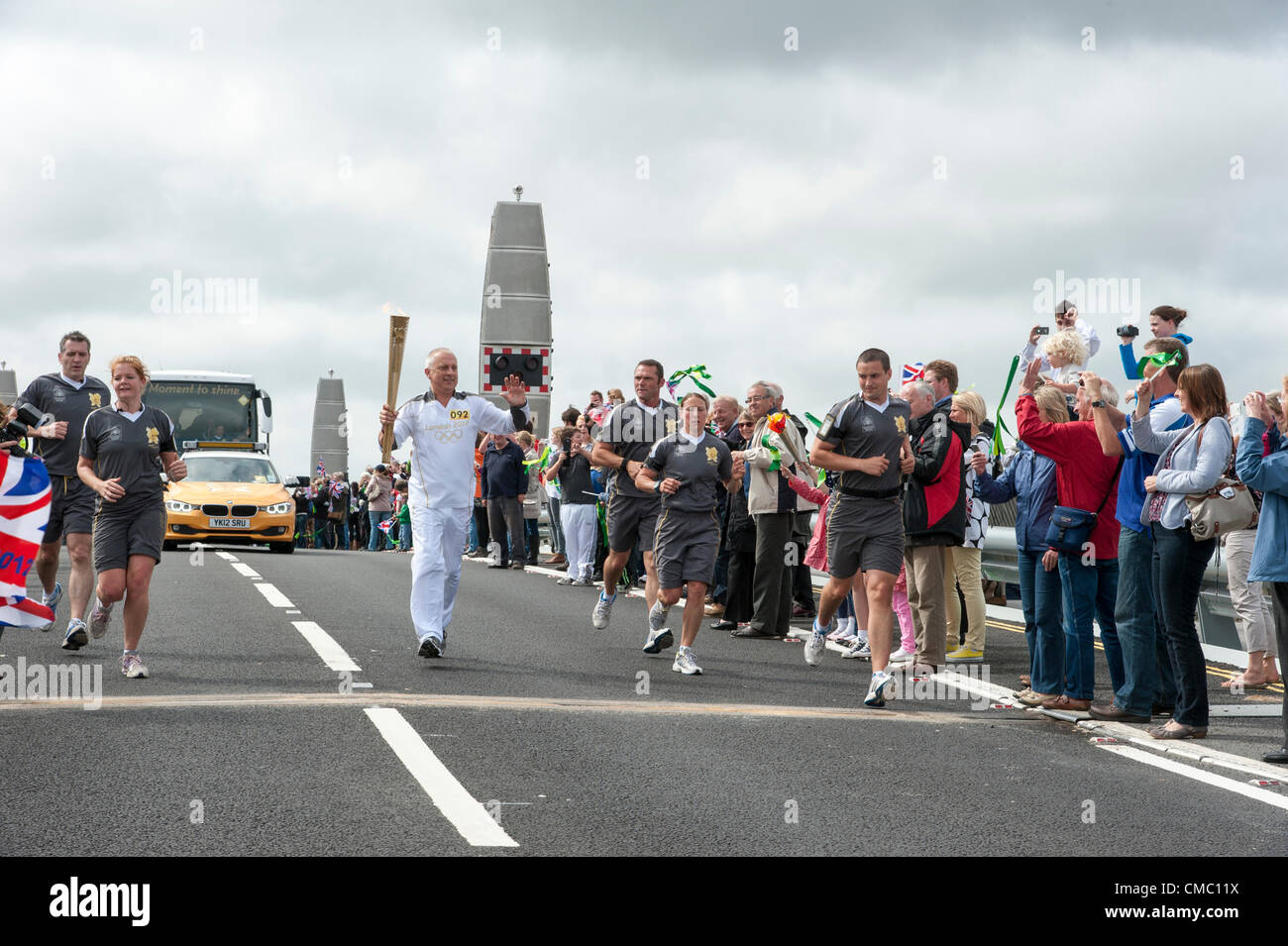 Poole, UK. 14 July, 2012. Torch bearer Barry Light crosses the Twin ...
