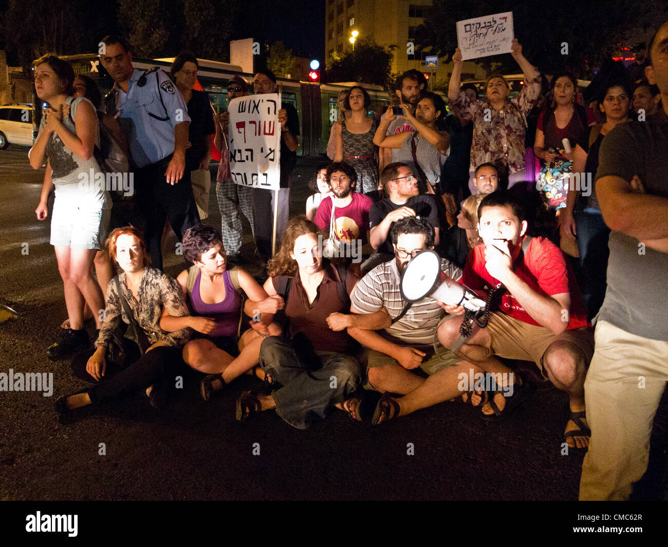 Social welfare activists, lit by vehicle headlights, sit on King George ...