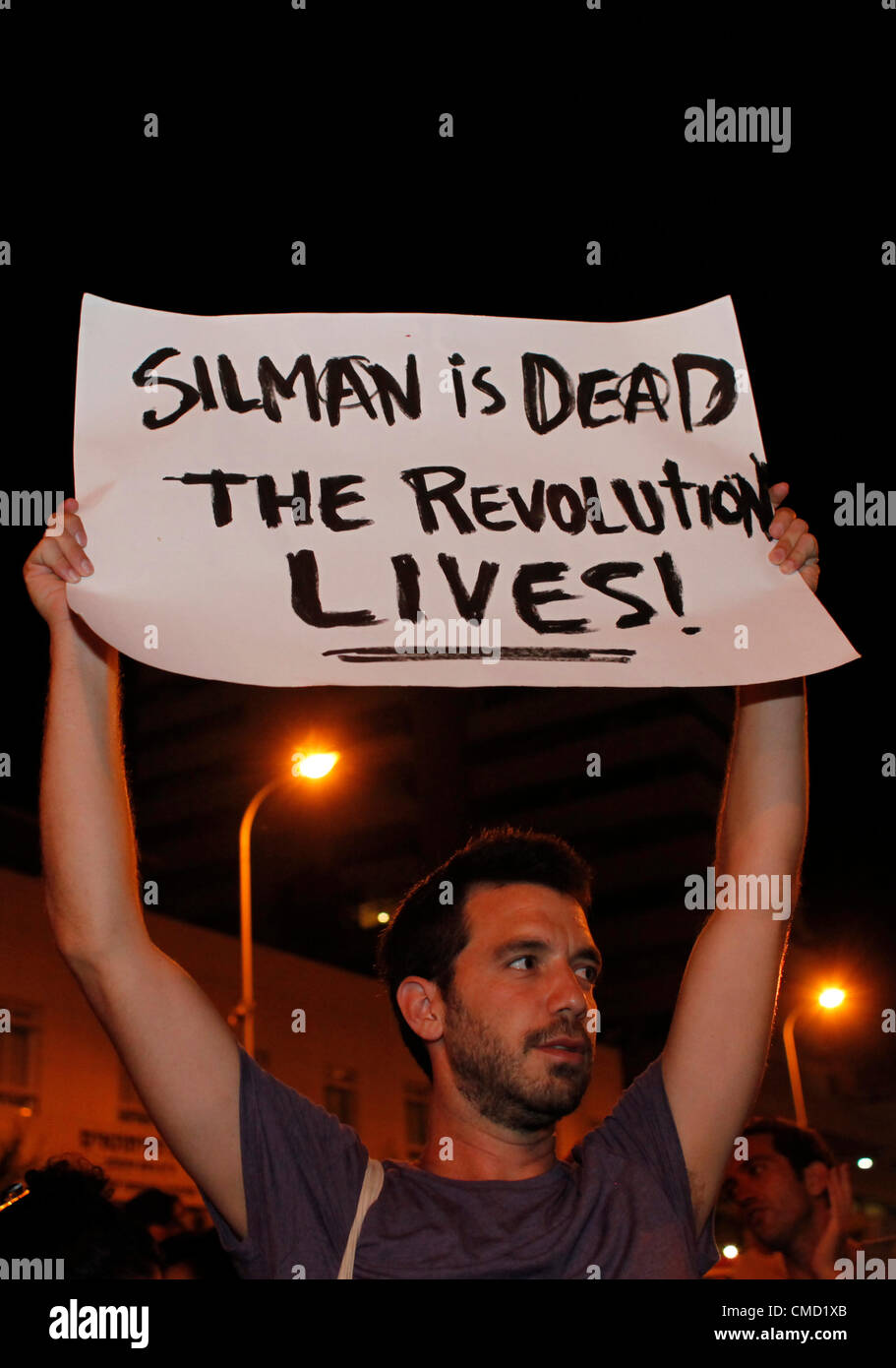 An Israeli demonstrator holds up a paperboard sign which reads "Silman ...
