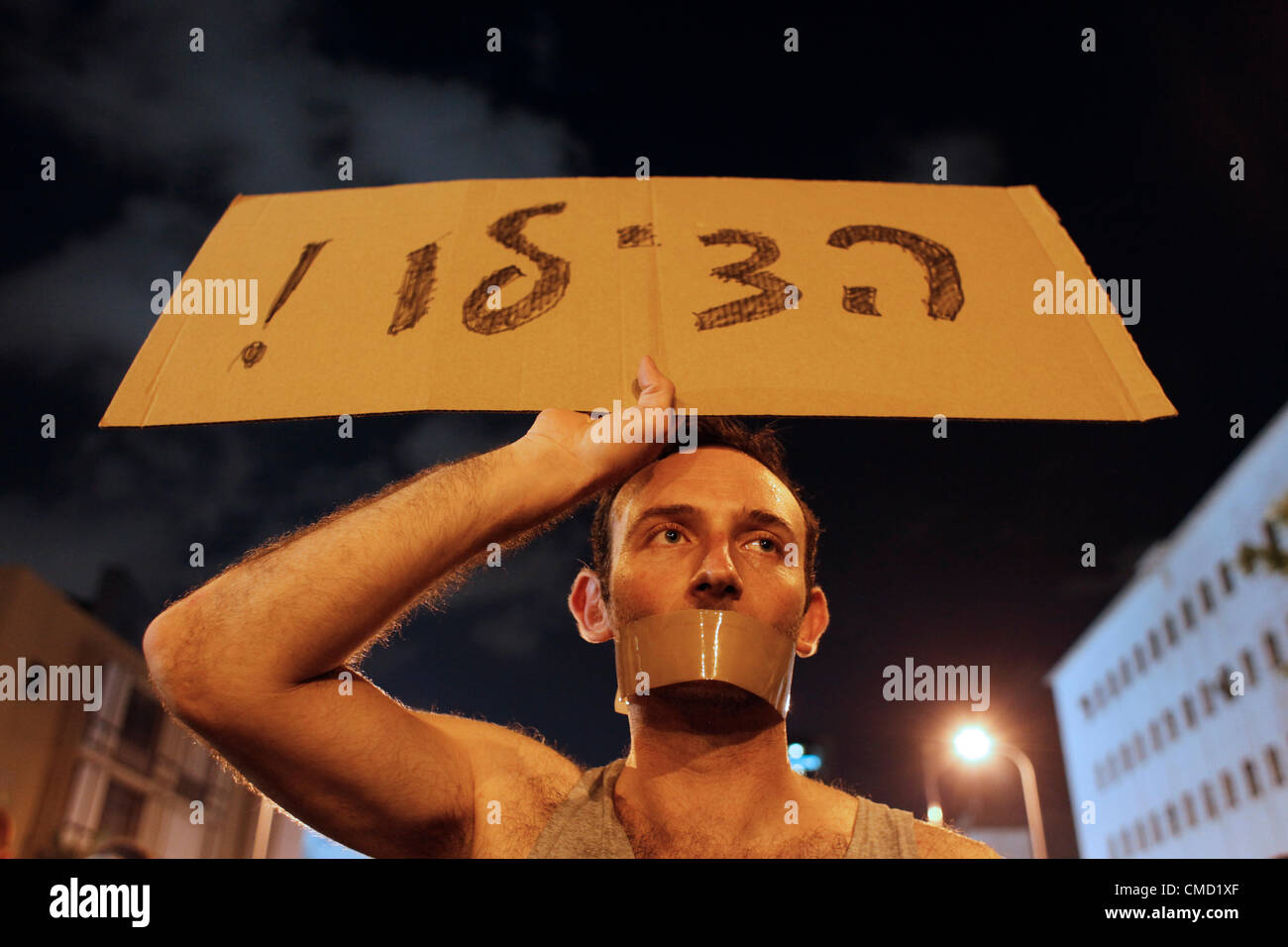 An Israeli demonstrator holds up a cardboard sign which reads "Help ...