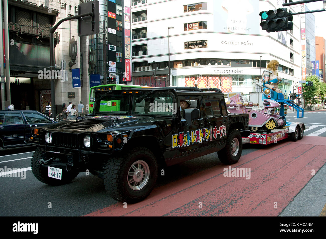 July 23 2012, Tokyo, Japan - A Hummer tows two robots in the streets of ...