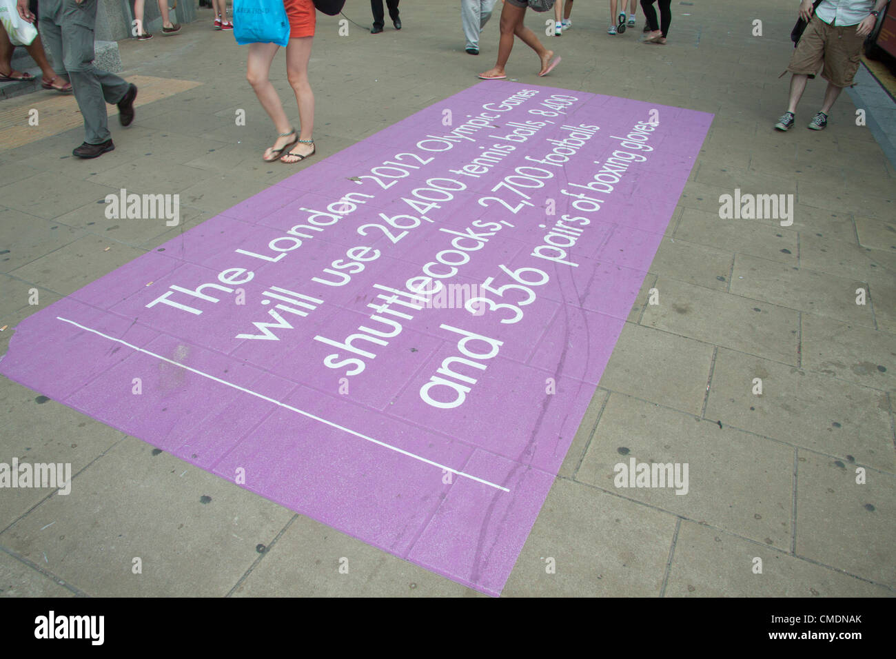 25th July, 2012. London UK. Pedestrians walk by a large Olympic sticker ...
