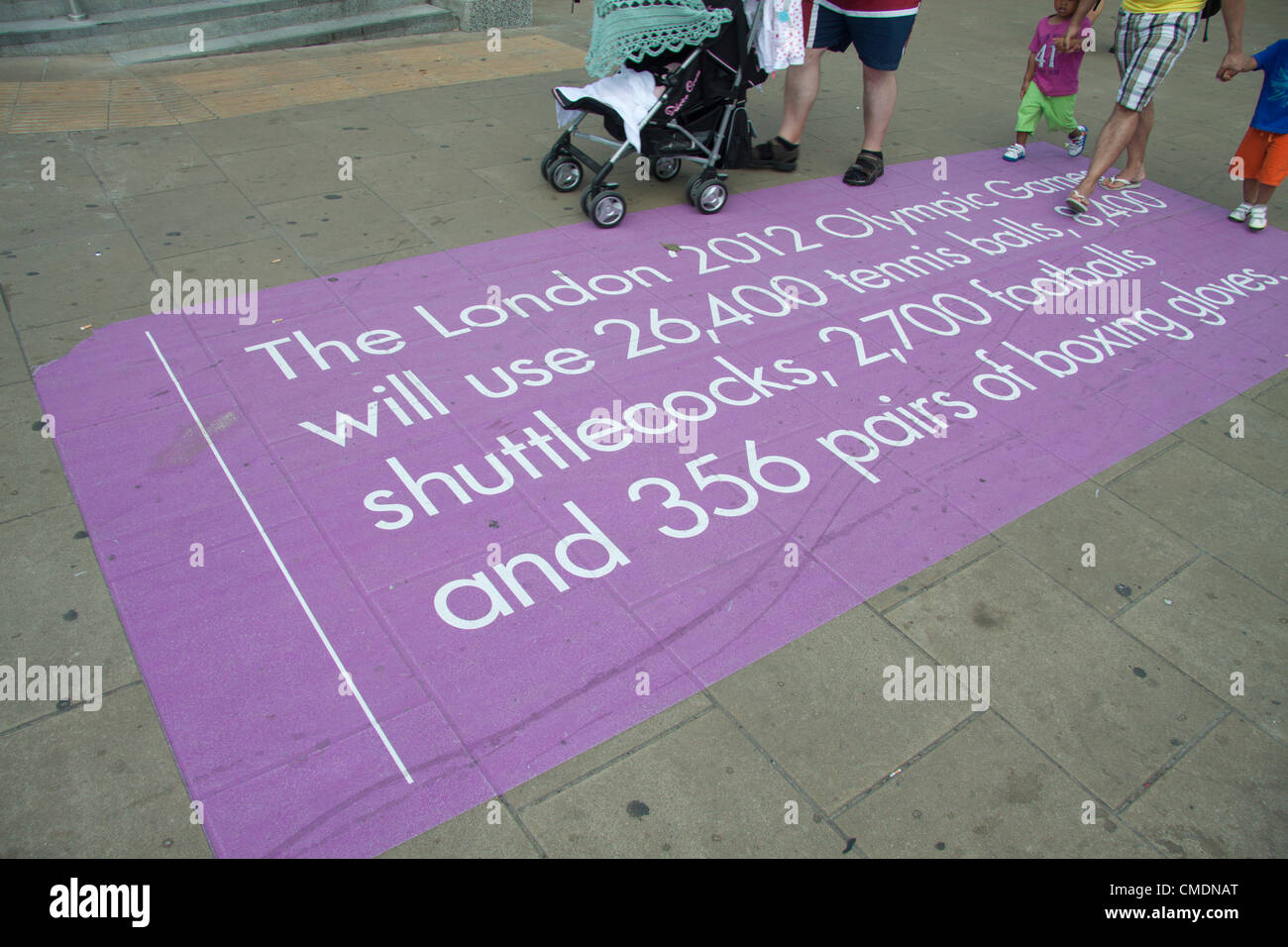 25th July, 2012. London UK. Pedestrians walk by a large Olympic sticker ...