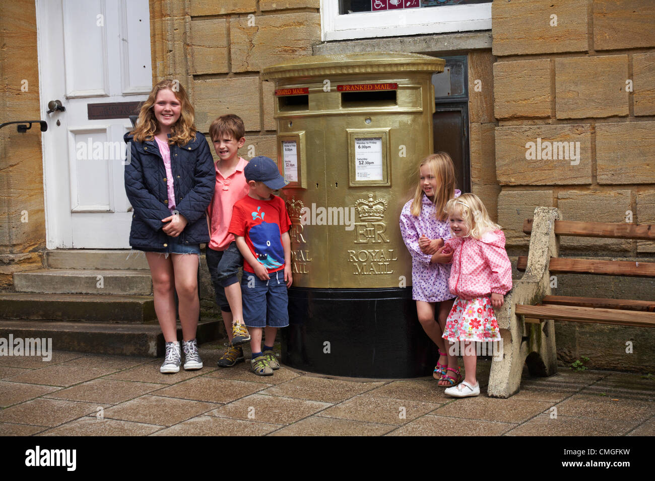 UK Monday 6 August 2012. Children pose in front of Royal Mail gold ...