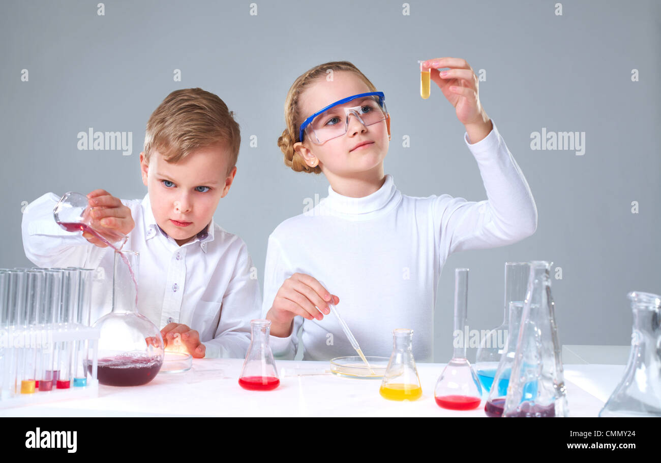 A little boy pouring liquid into a tube and his assistant shaking a ...