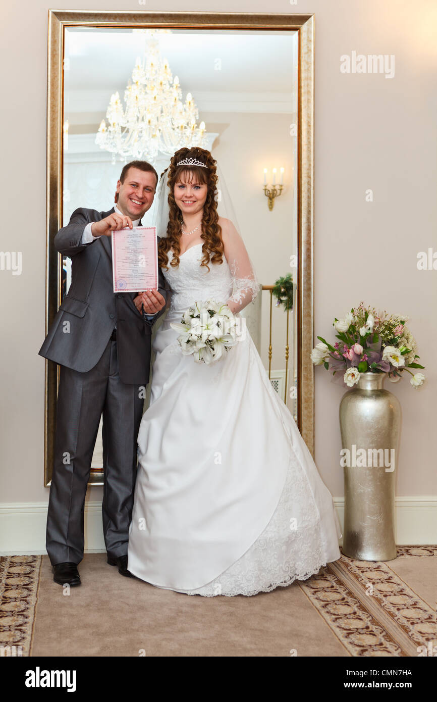 Happy Caucasian newlywed Russian couple showing marriage certificate ...