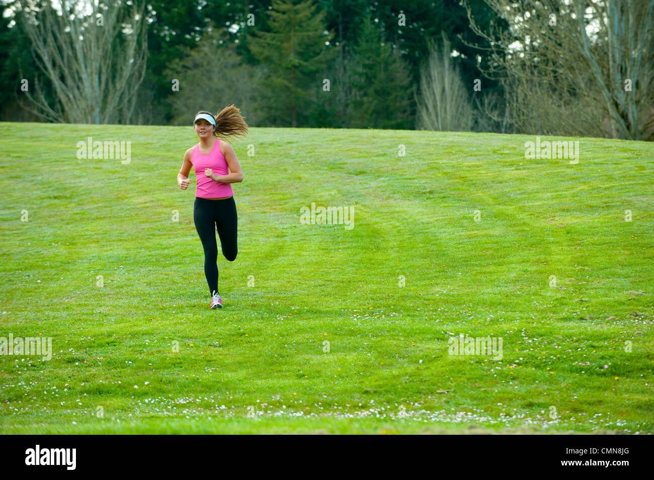 Mixed race runner jogging across field Stock Photo - Alamy