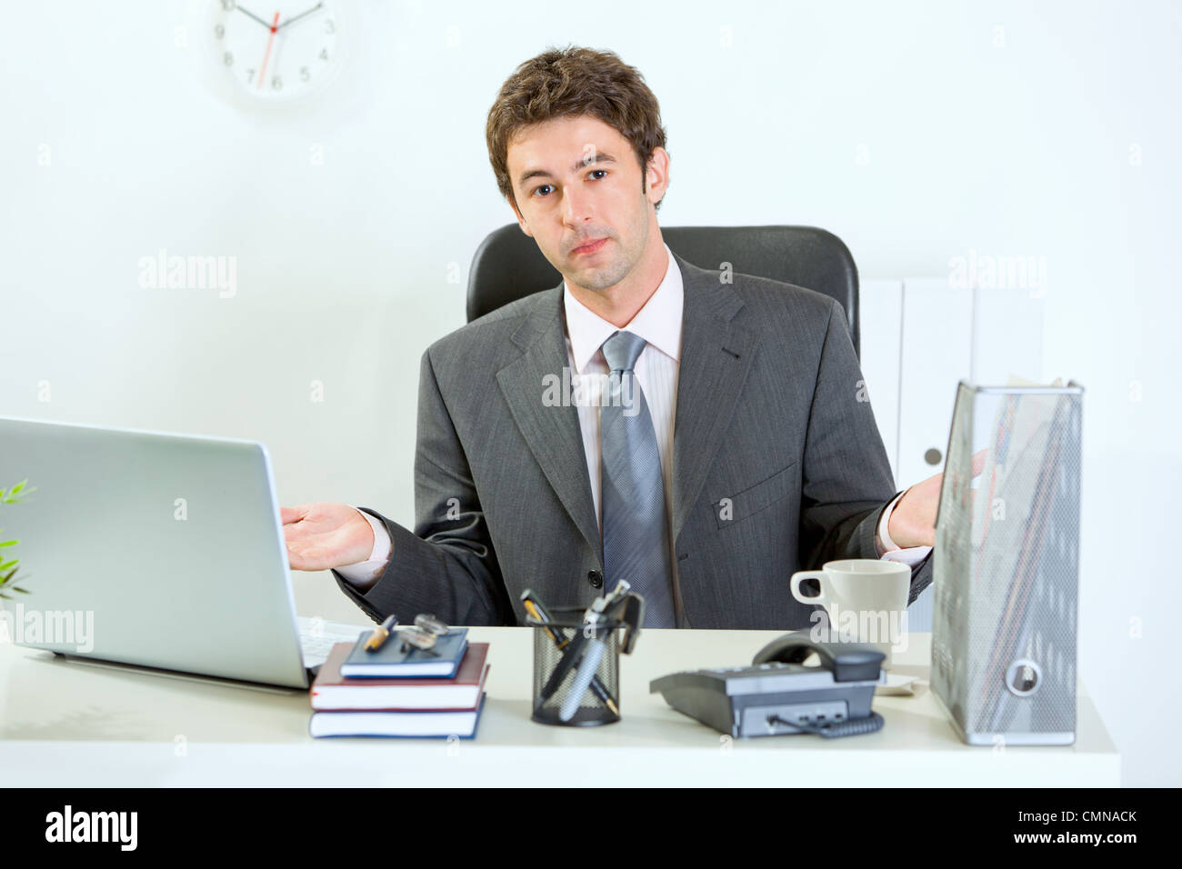 Confused modern business man sitting at office desk Stock Photo - Alamy
