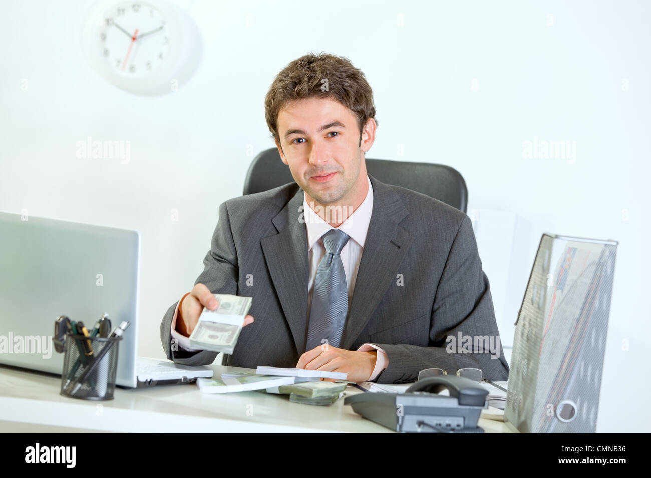 Modern businessman sitting at office desk and giving money packs Stock ...