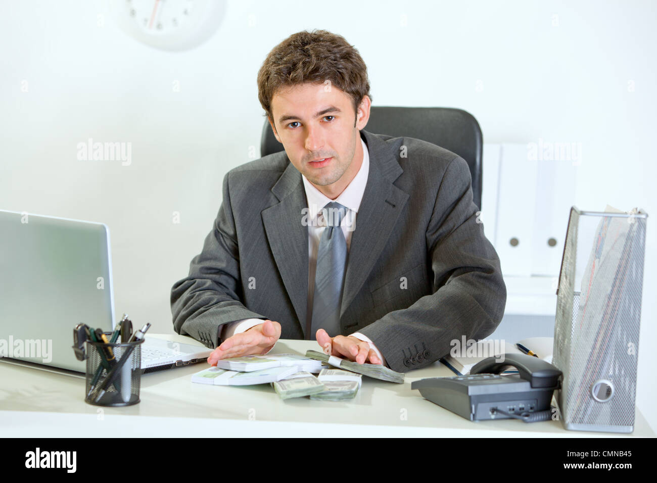 Modern business man sitting at office desk and giving money packs Stock ...