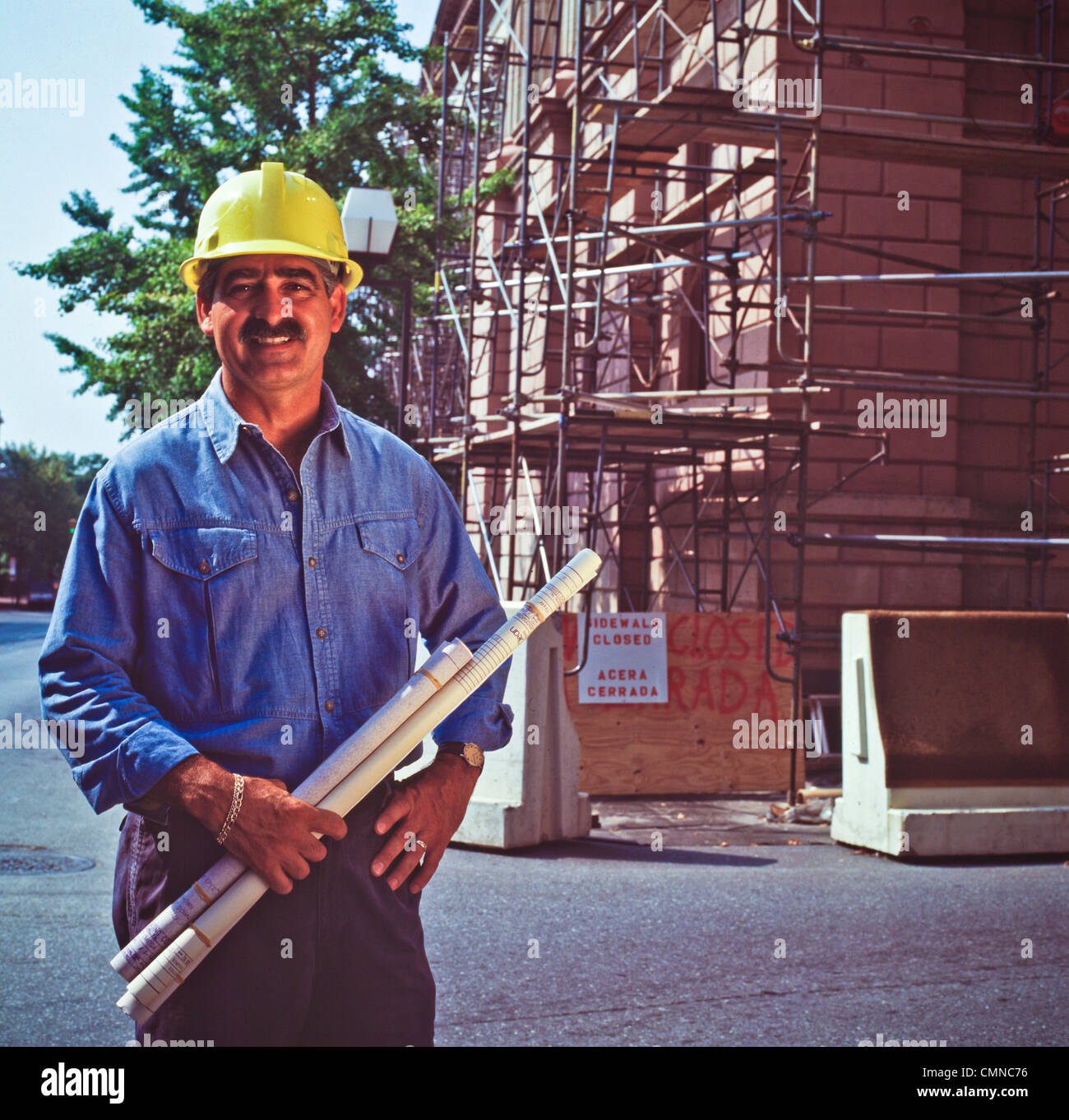 Building, construction foreman with blueprints, yellow hard hat, on ...