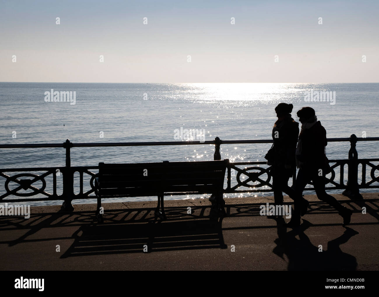 Two people walking on Hove promenade in bright sunshine Stock Photo - Alamy