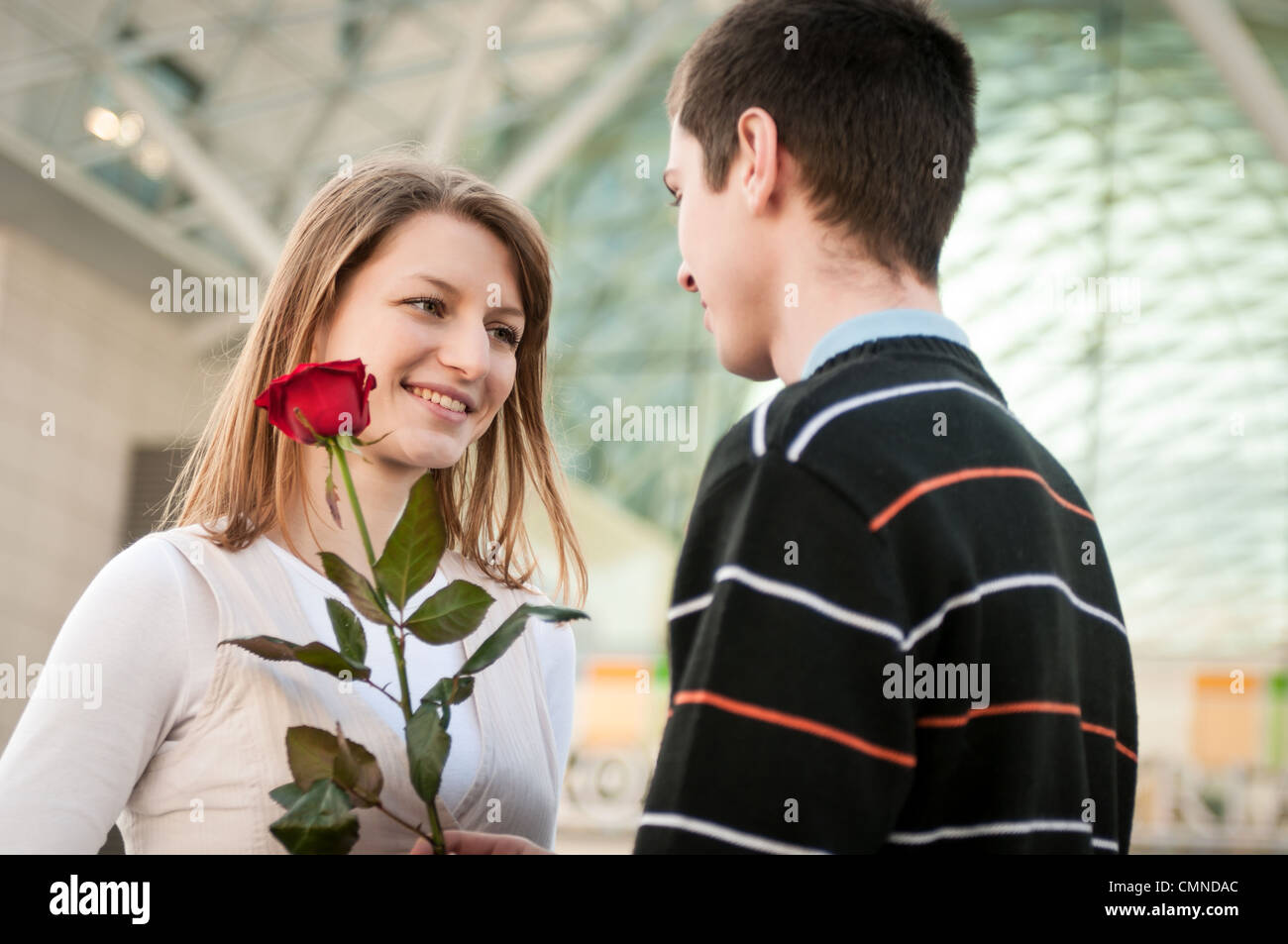 Young man handing over a flower (red rose) to woman - outdoor lifestyle ...