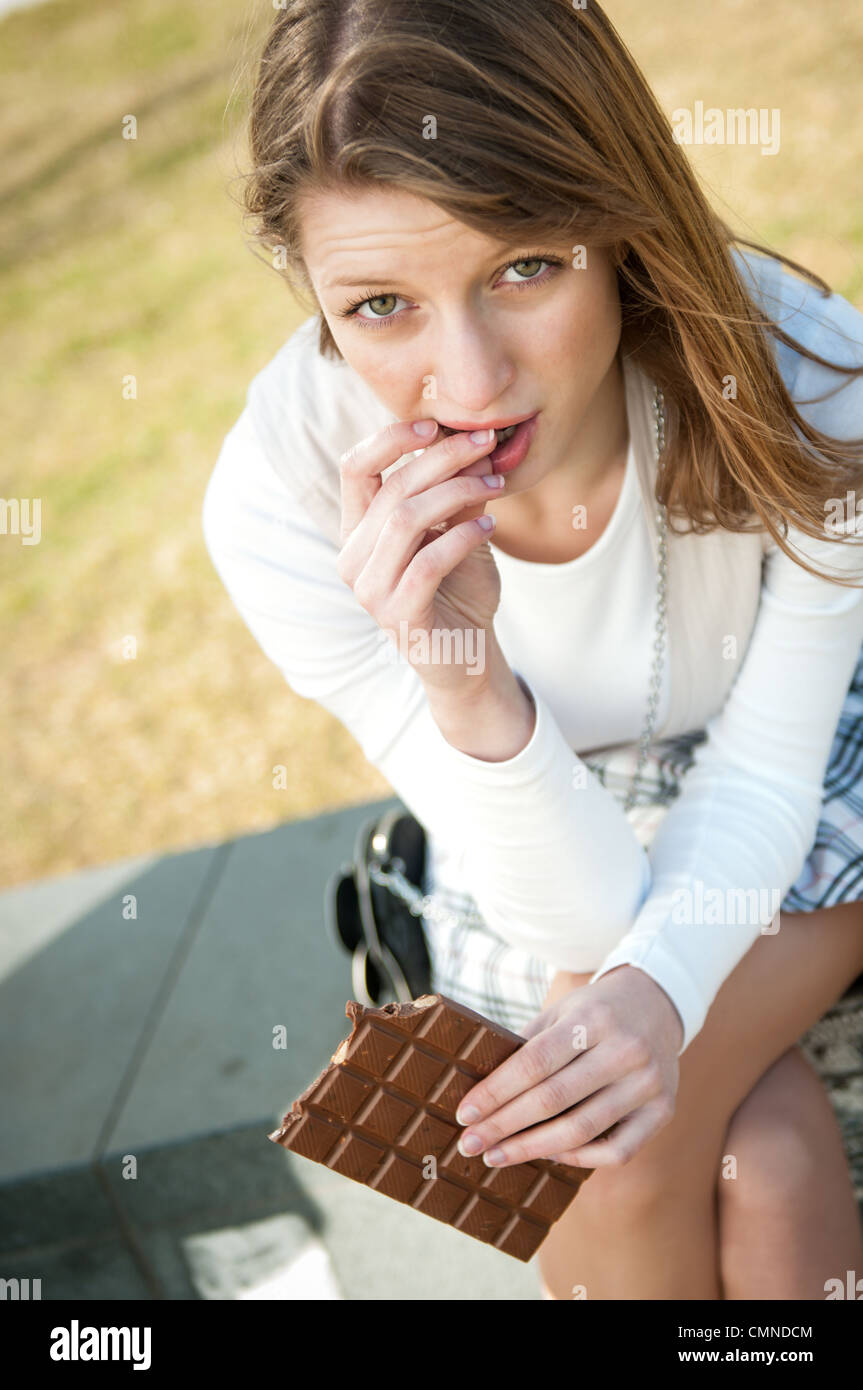 Depression - outdoor portrait of young worried woman eating chocolate ...