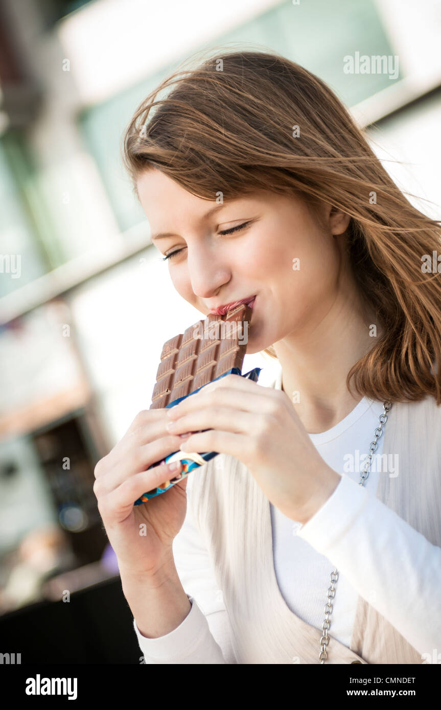 Lifestyle outdoor scene - young beautiful woman eating chocolate Stock ...