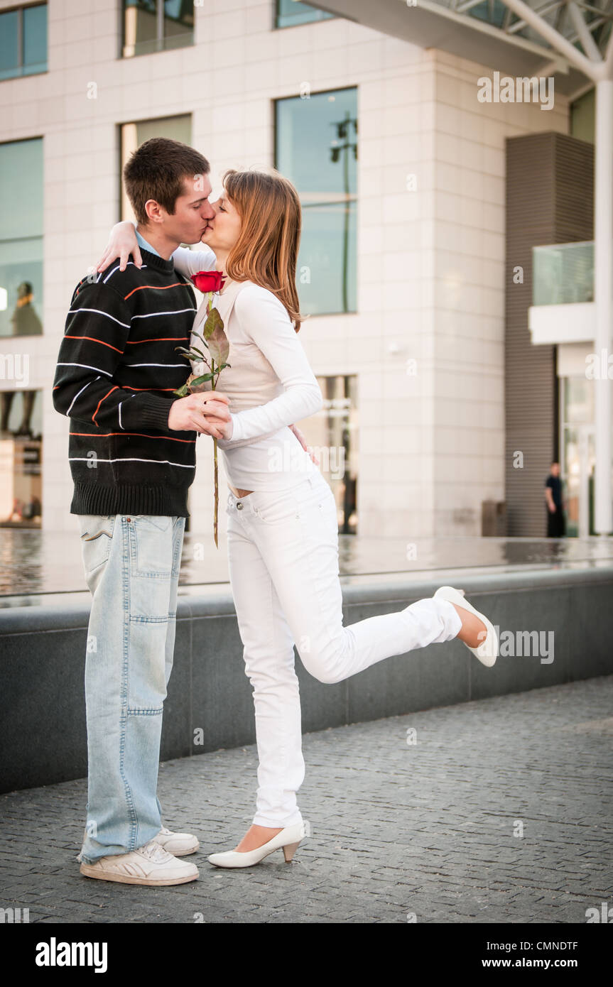 Young man handing over a flower (red rose) to woman on street Stock ...
