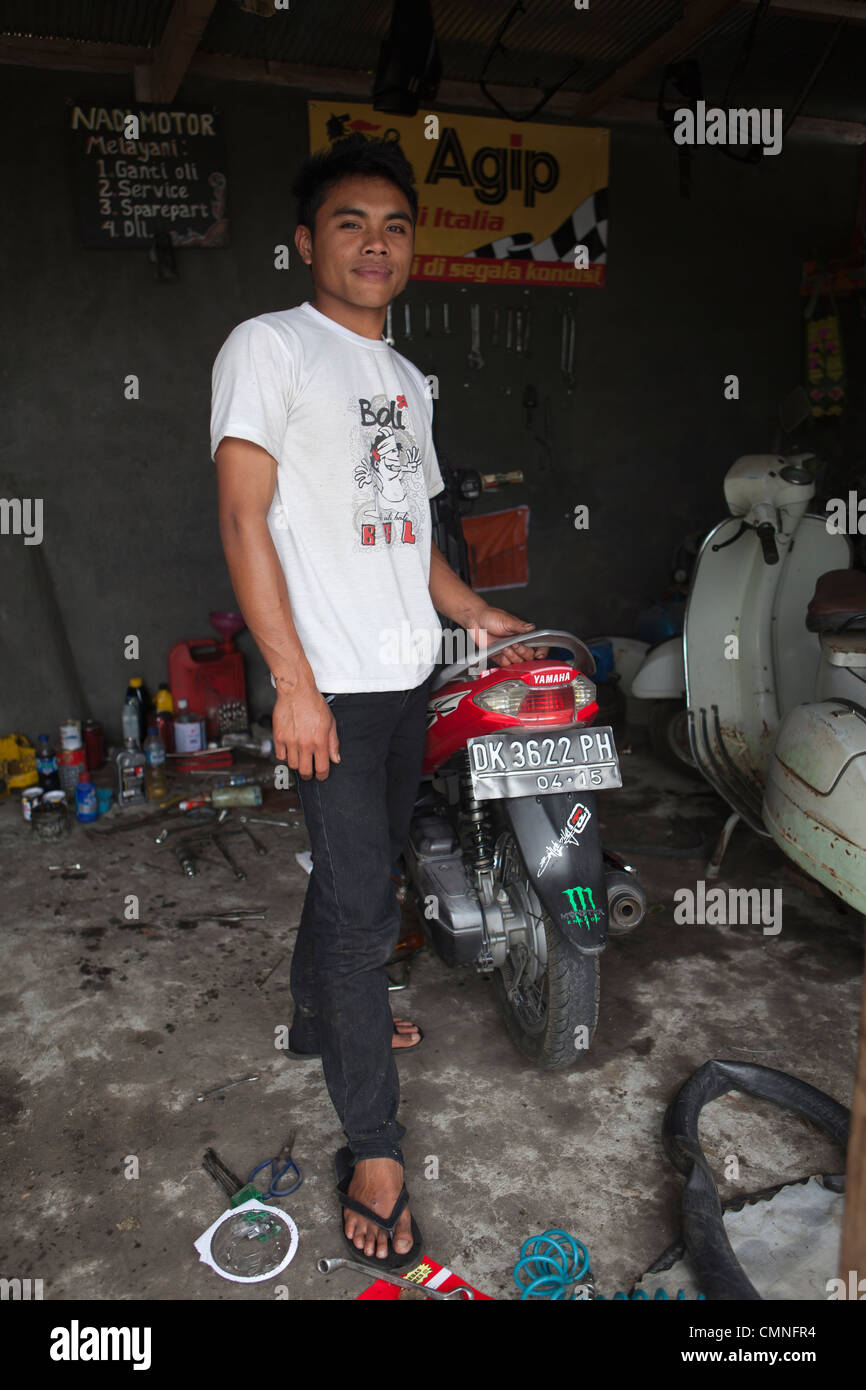 Young Balinese man working on a motorbike in a garage, Bali, Indonesia ...