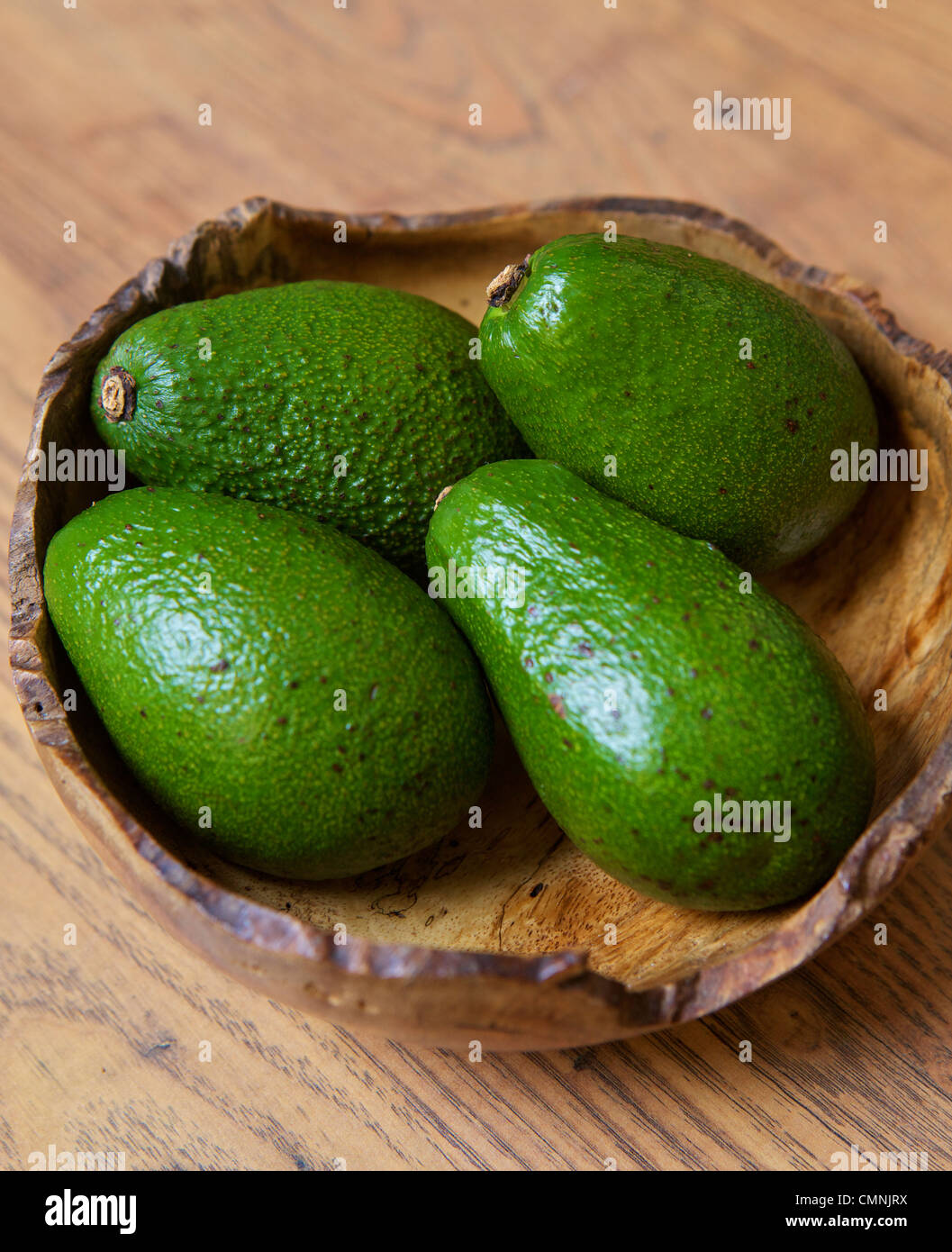 Four avocados in a wooden bowl Stock Photo - Alamy