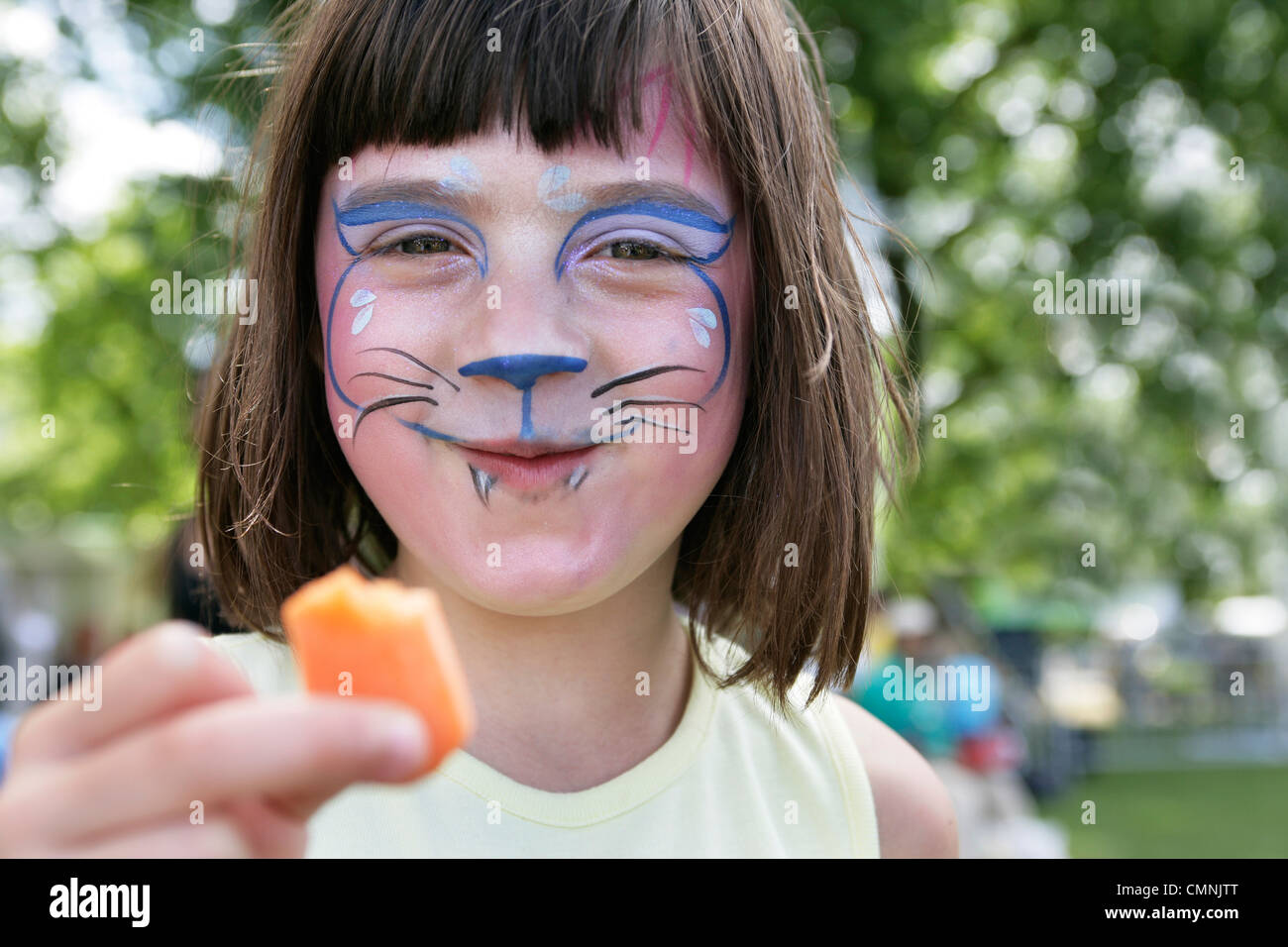 Girl with her face painted eating raw carrots at the Food Standard's ...