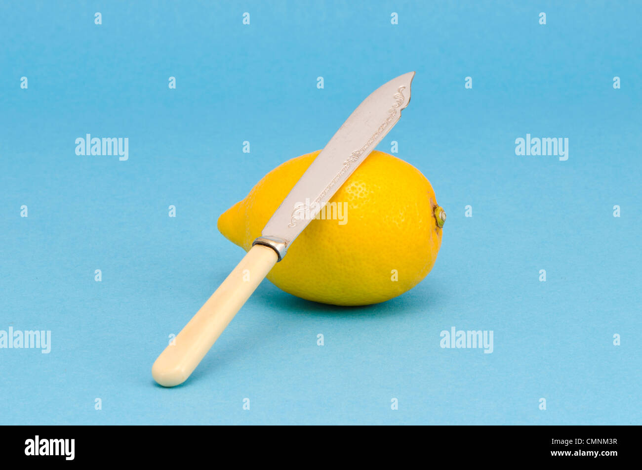 one yellow lemon with knife on azure background Stock Photo - Alamy