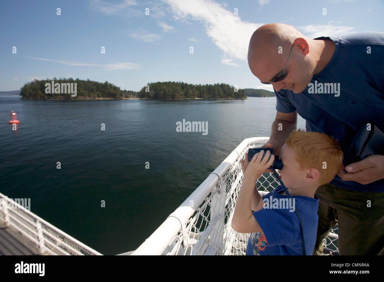 Father and son look through binoculars from the deck of the Salt Spring ...