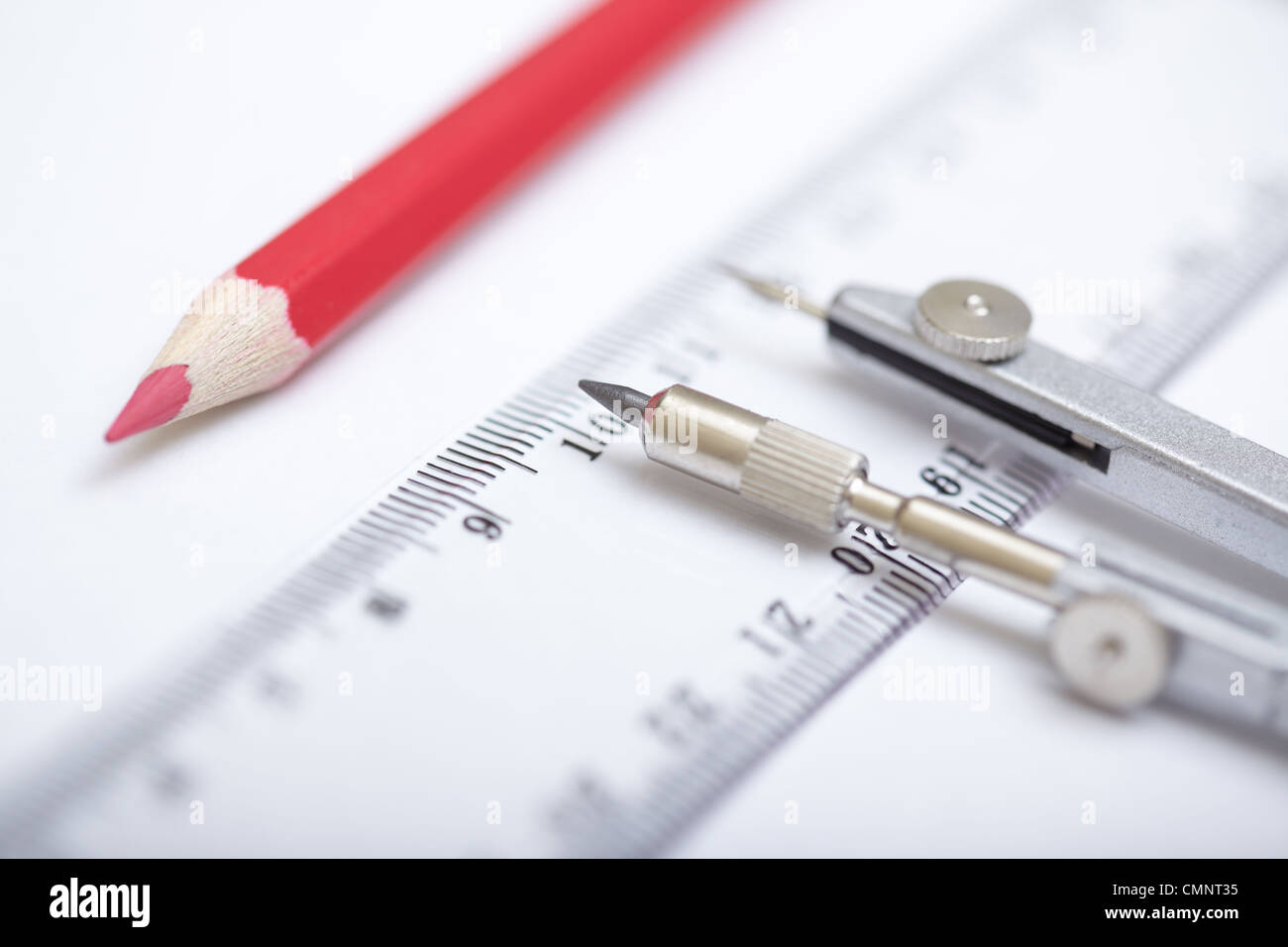 Red pencil with compasses and rulers on a white paper. Extremely close ...