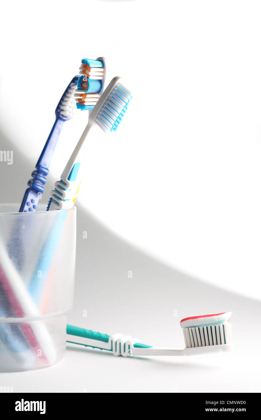 Some toothbrushes in a plastic glass Stock Photo - Alamy