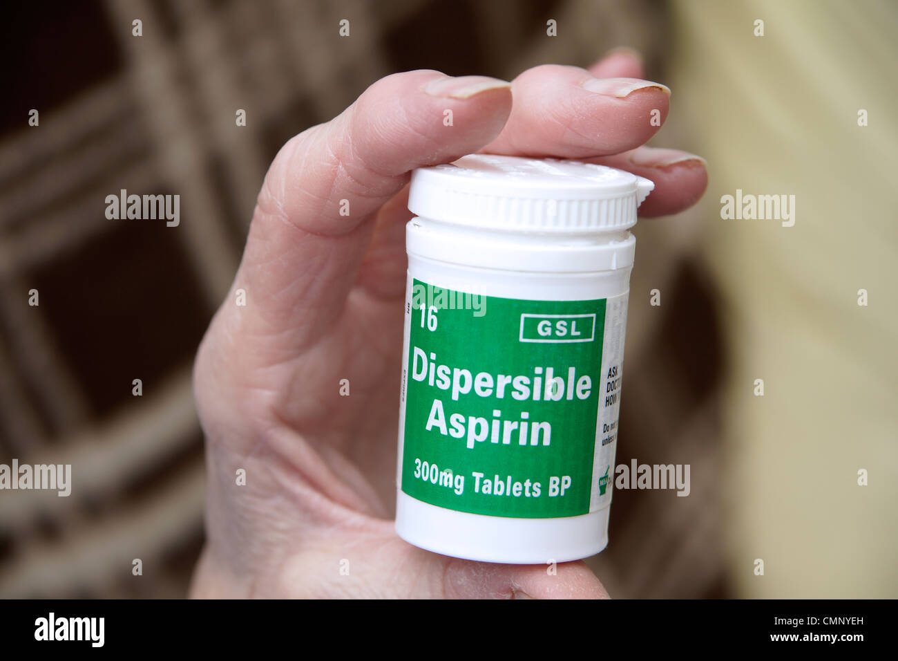 Elderly woman holding a bottle of dispersible aspirins - taken for many ...