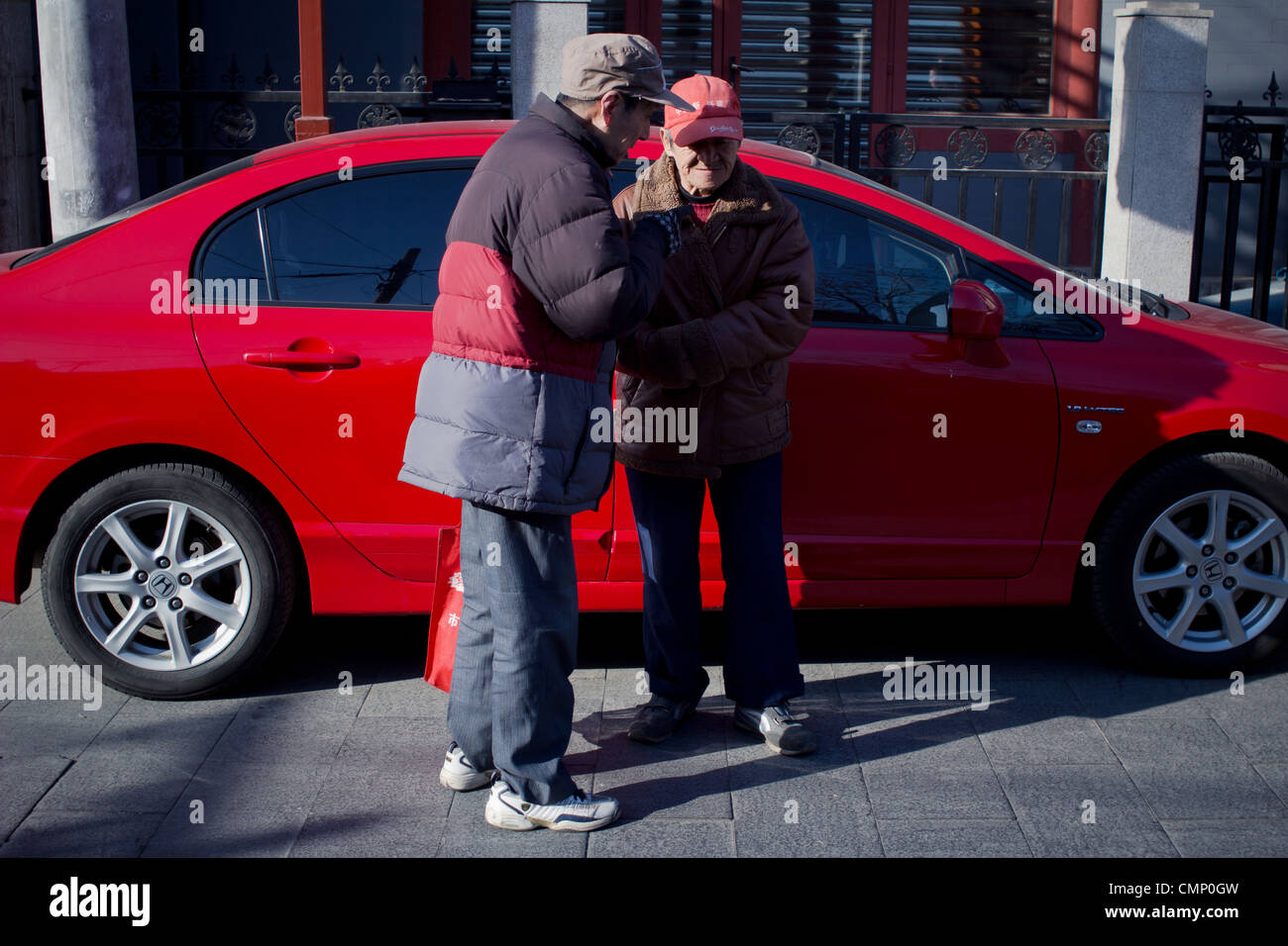 two old men talking beside a red car in a Hutong of Beijing Stock Photo ...