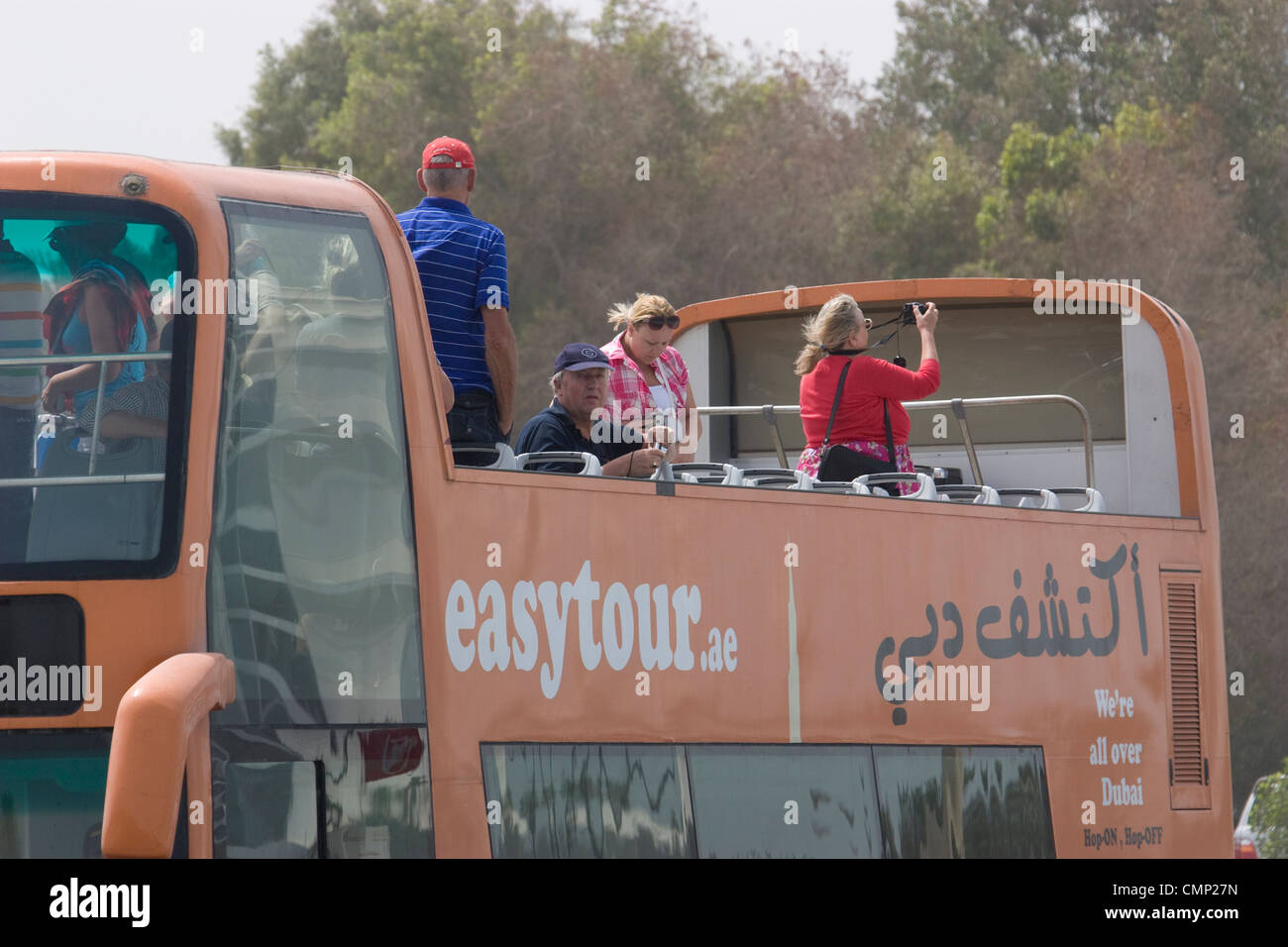 Tourists standing and taking photos from the top deck of an EasyTour ...