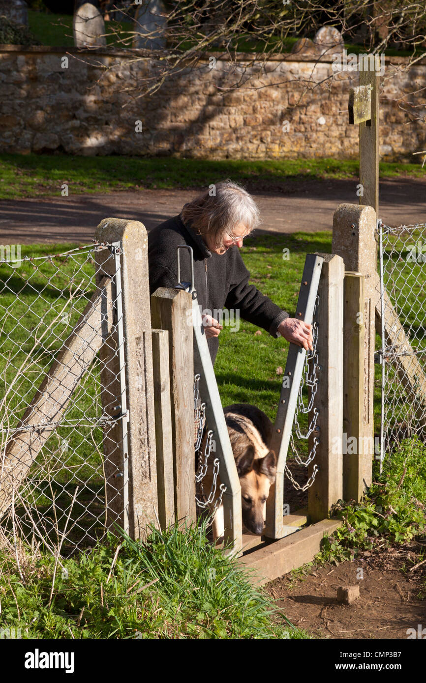 Woman opening spring-loaded gate for her dog, Dowlish Wake, Somerset ...
