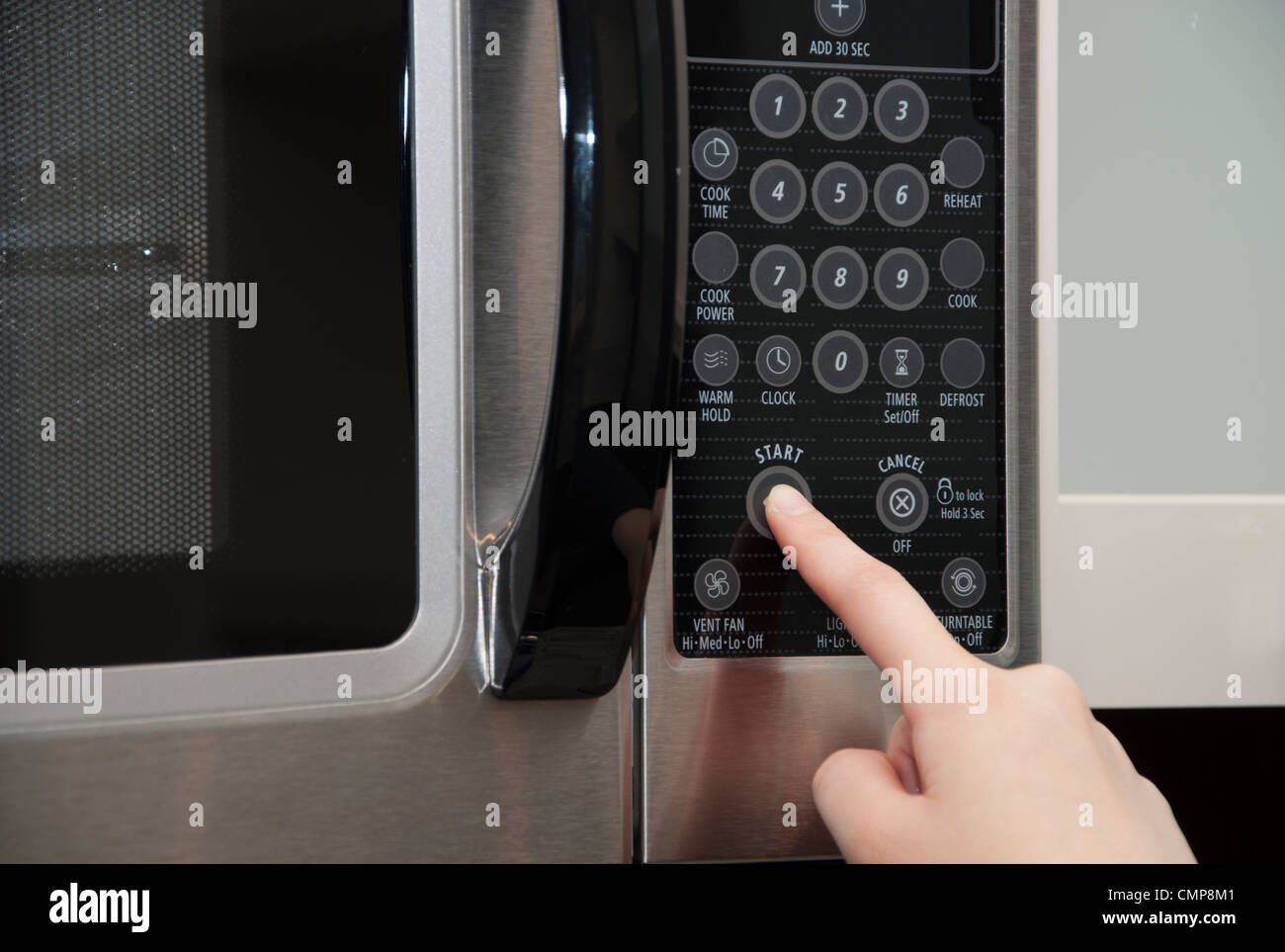 Pressing start button on microwave Stock Photo - Alamy