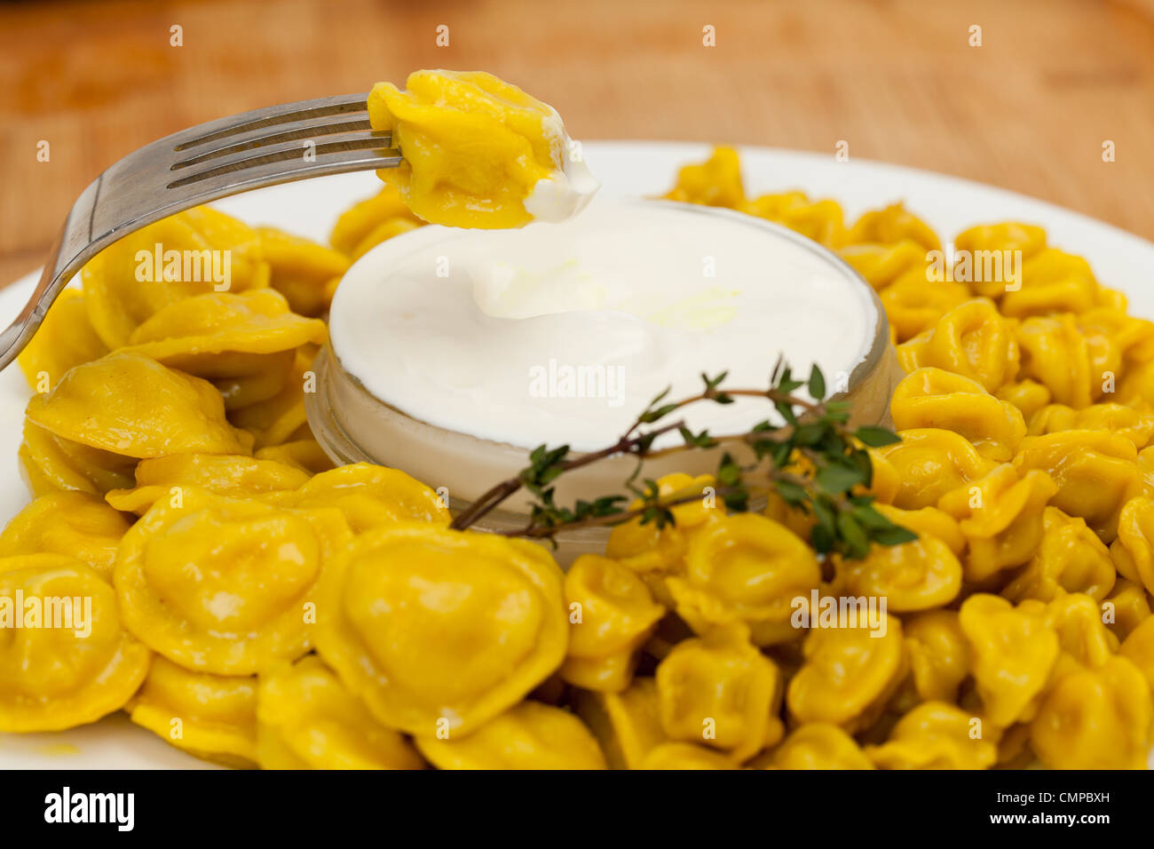 Yellow dumplings with sour cream on a plate closeup Stock Photo - Alamy