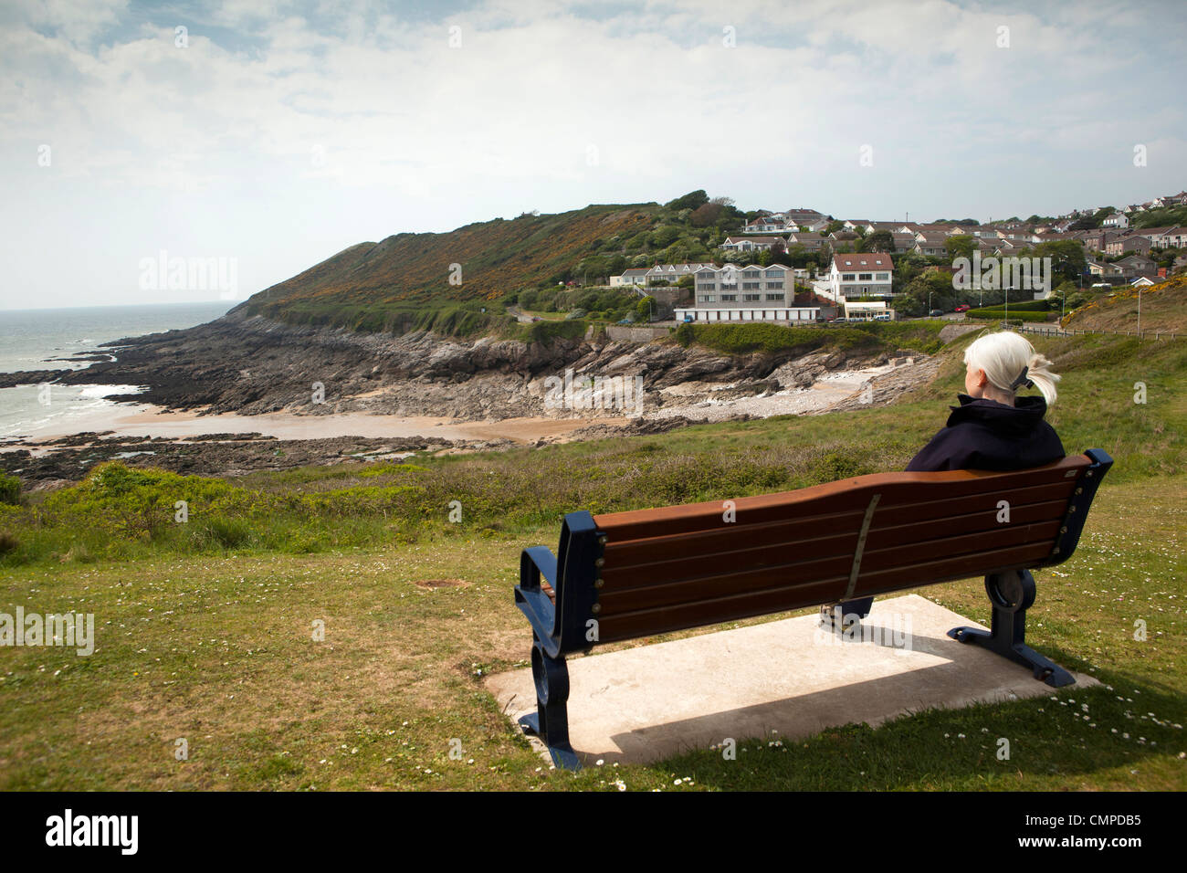 UK, Wales, Swansea, Mumbles, Gower, visitor sitting on bench in ...