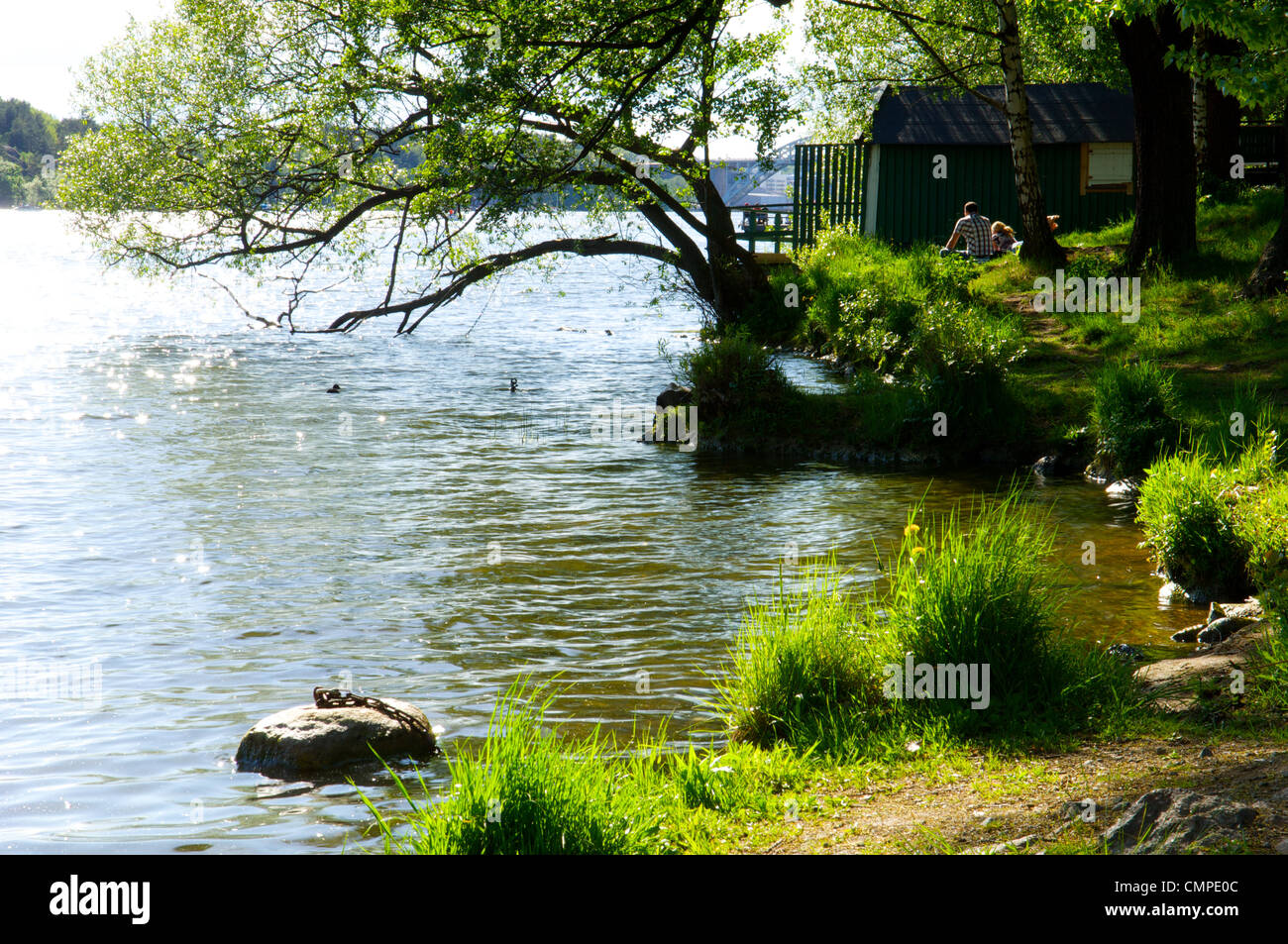 People resting by tree, hut and river Stock Photo - Alamy