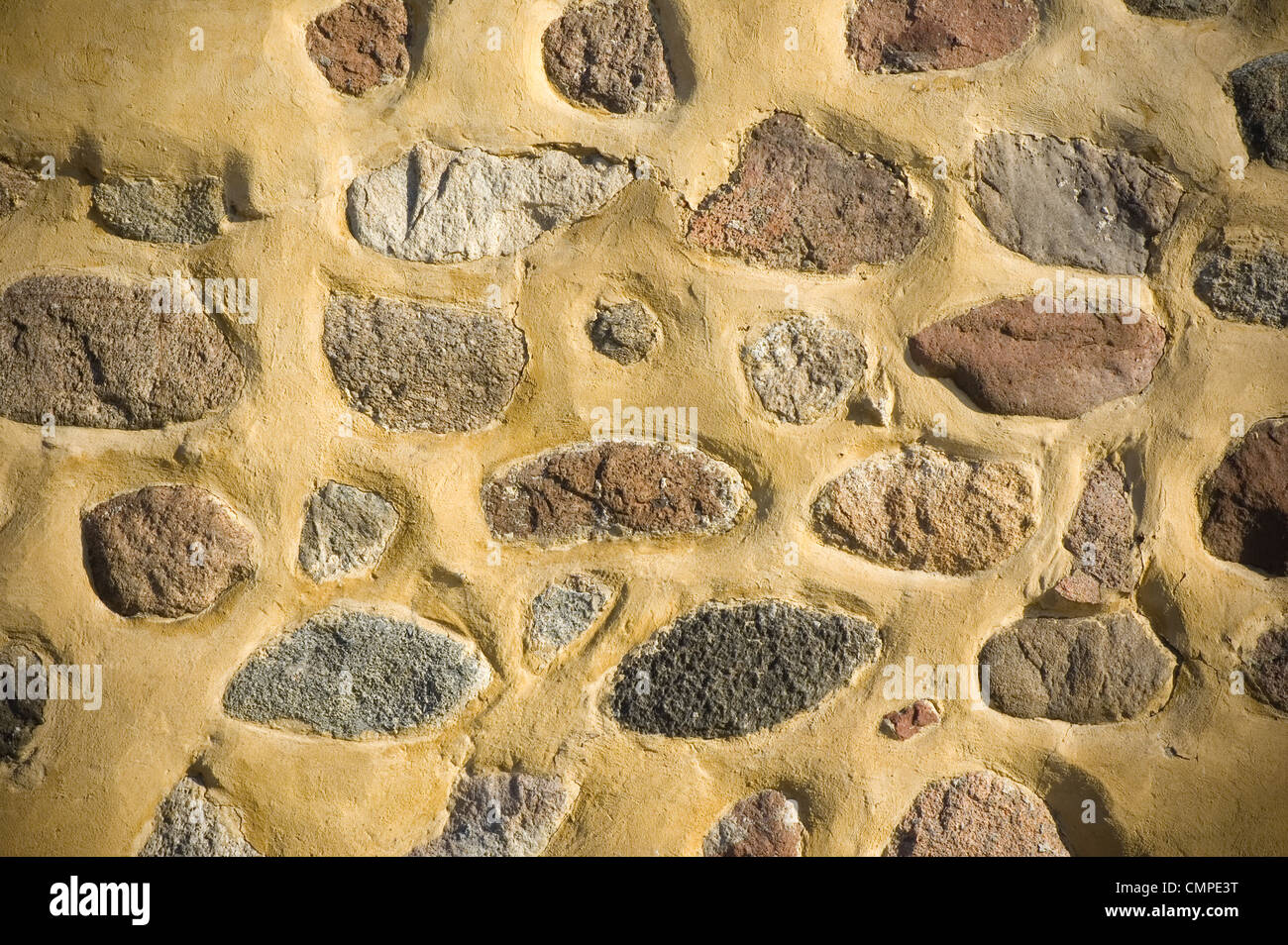 Yellow plastered wall with stones Stock Photo - Alamy