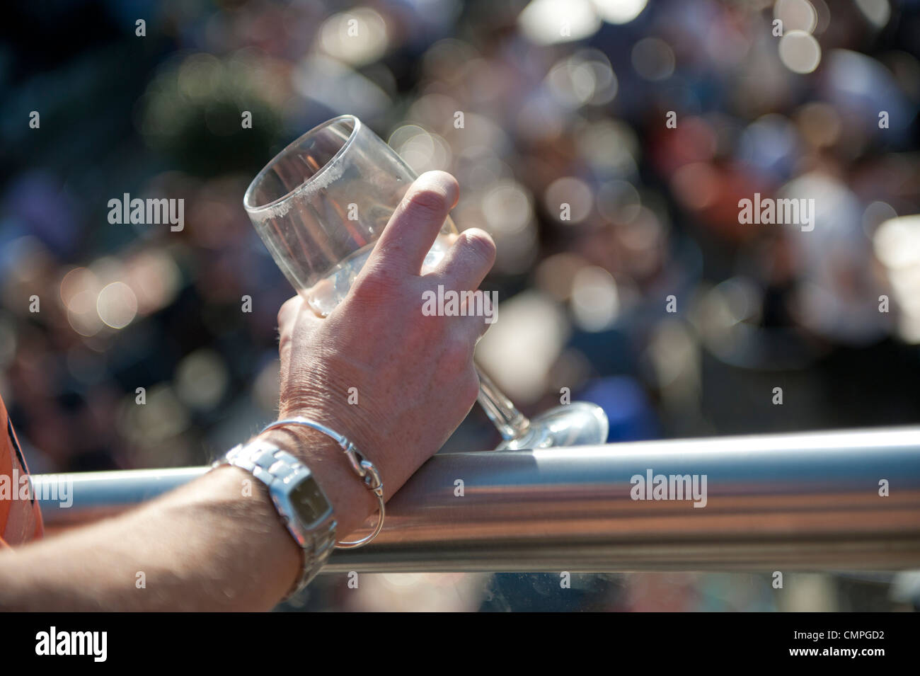 A woman's hand holds a partly empty wine glass over a railing over a ...