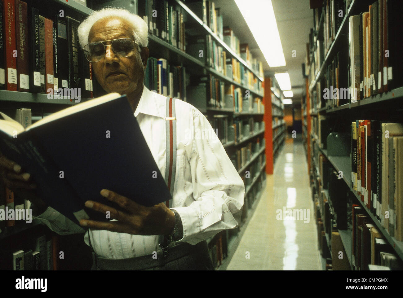 Senior Man in Library Reading Book Stock Photo - Alamy