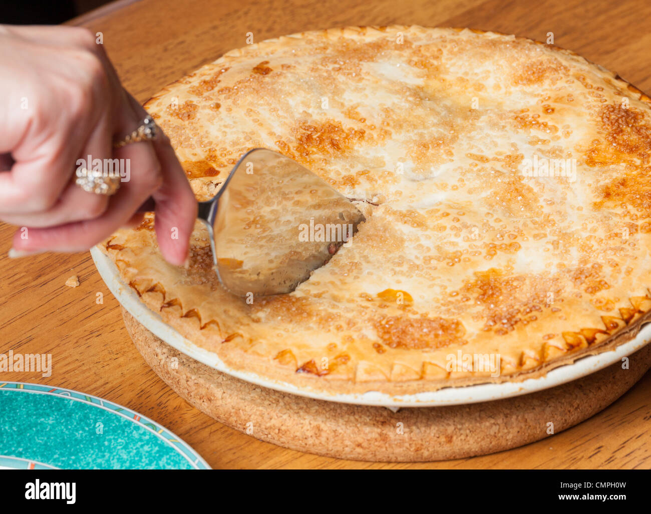 Home made baked fruit pie from oven and on table being cut with knife ...