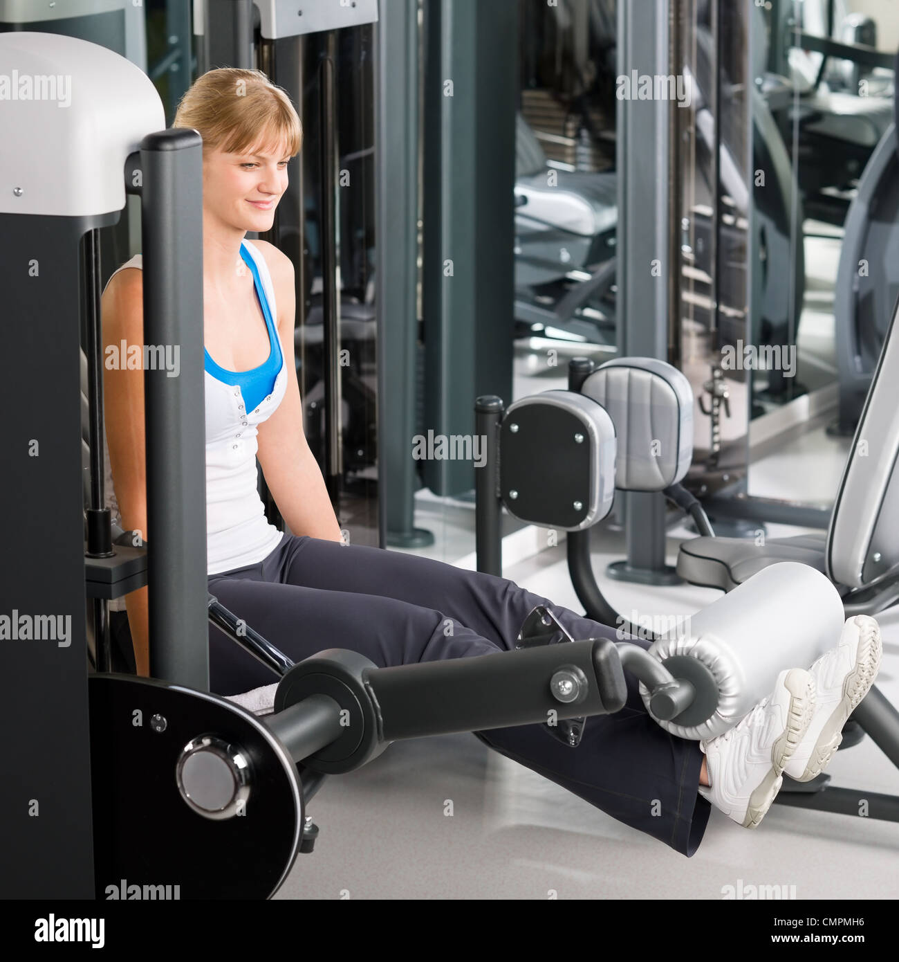 Fitness center young woman exercise legs on gym machine workout Stock ...